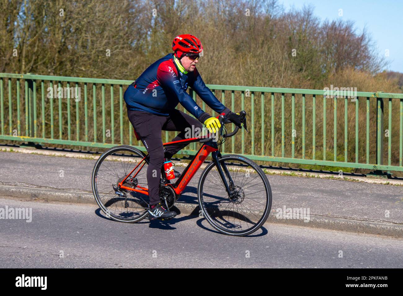 Cyclist riding Red Trek cycle crossing motorway bridge in Greater ...