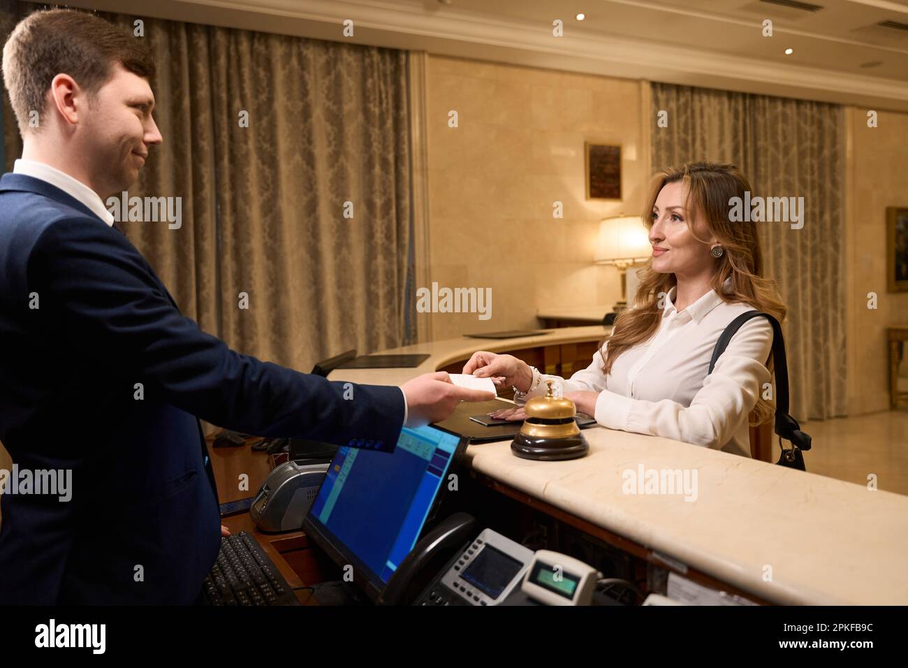 Cute traveler checks in at the hotel reception desk Stock Photo - Alamy