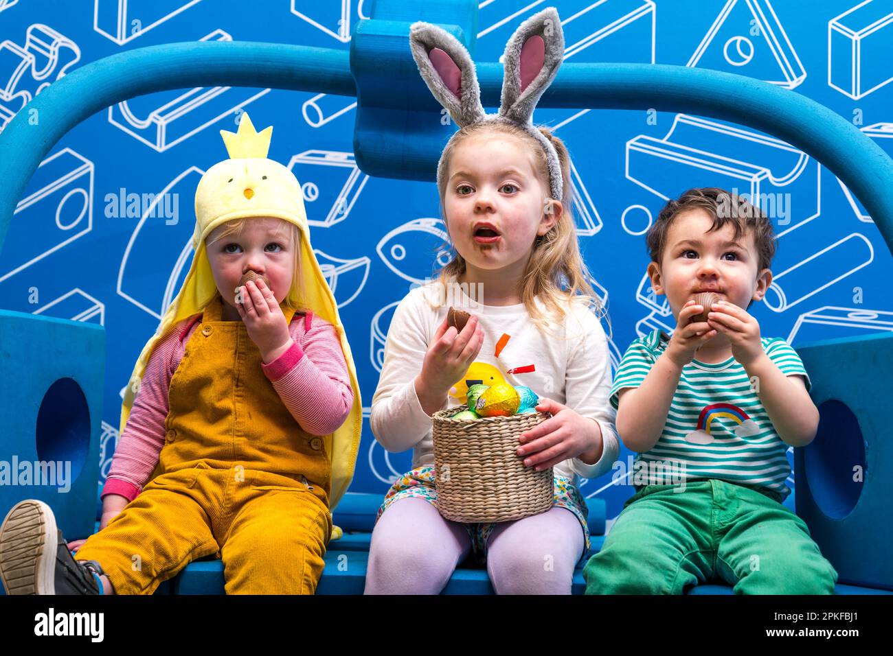 Three happy young children eating chocolate Easter eggs at Edinburgh ...