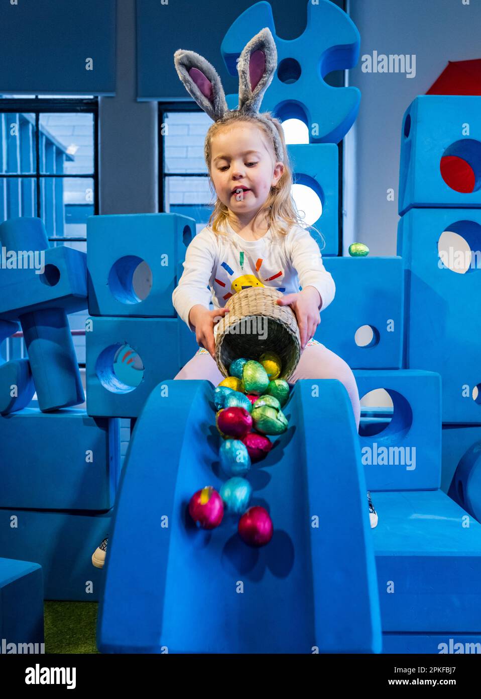 Young girl having fun rolling chocolate Easter eggs down slide ...