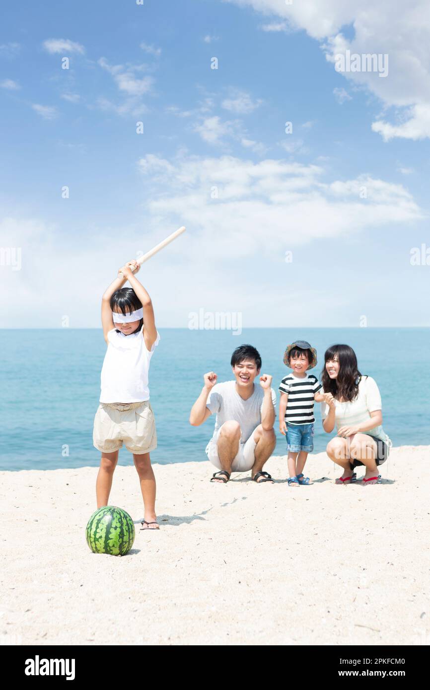 A family splitting a watermelon on the beach Stock Photo - Alamy