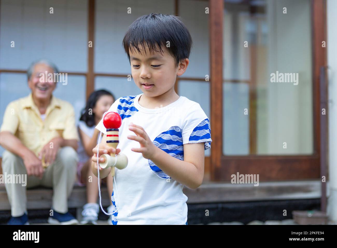 A boy playing kendama with his grandfather and sister Stock Photo - Alamy