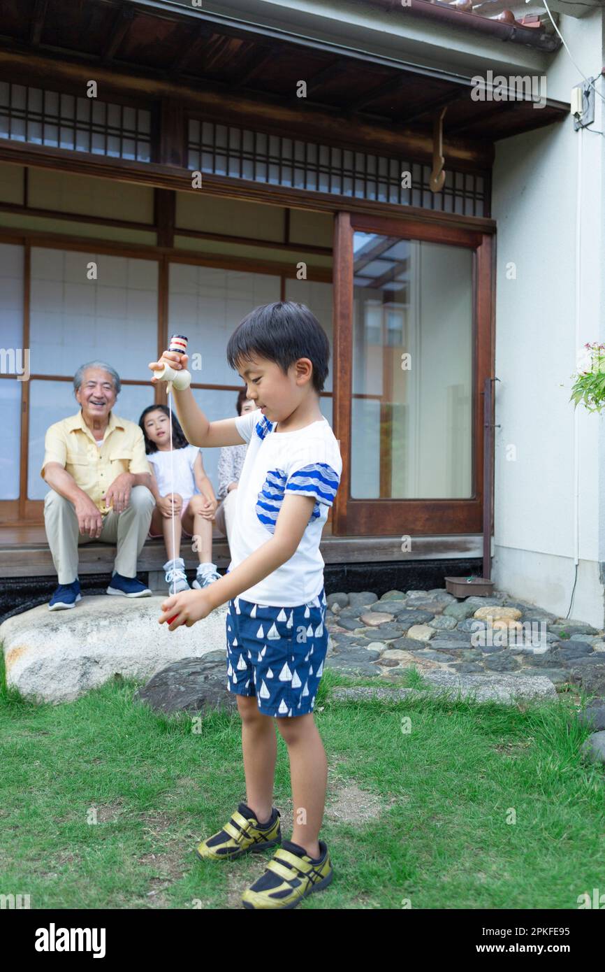 A boy playing kendama with his grandfather and sister Stock Photo - Alamy
