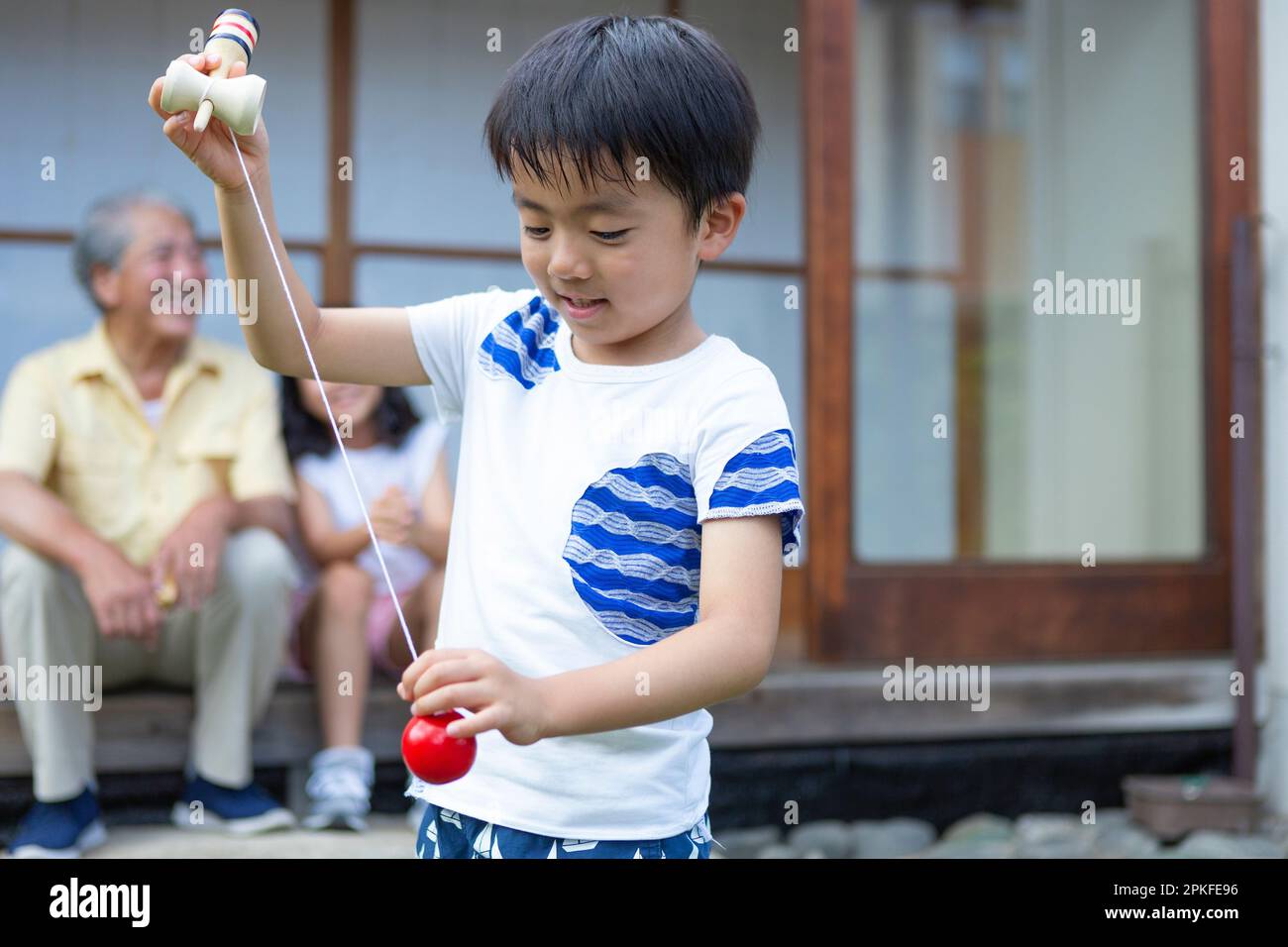 A boy playing kendama with his grandfather and sister Stock Photo - Alamy