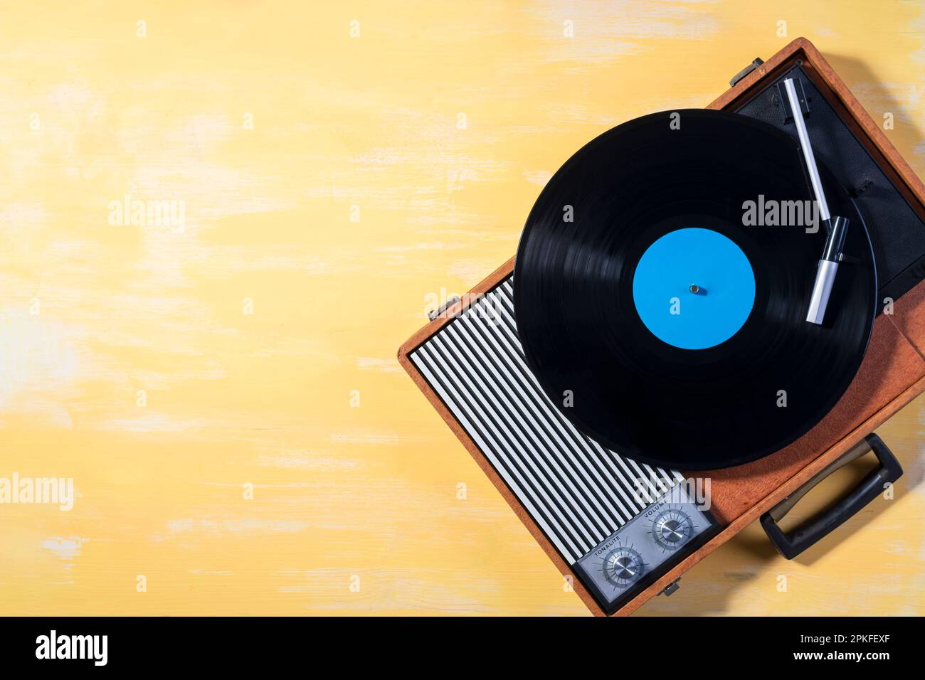 Old gramophone with a vinyl record on yellow wooden table, top view ...