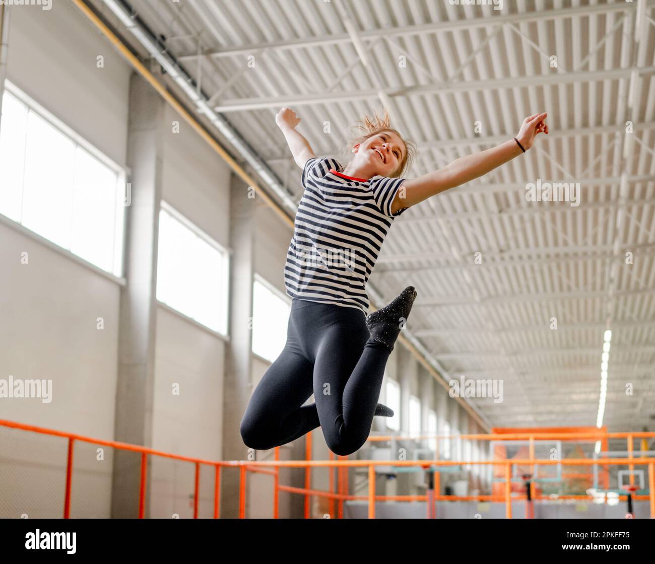 Pretty girl in trampoline park jumping and making split pose in air ...