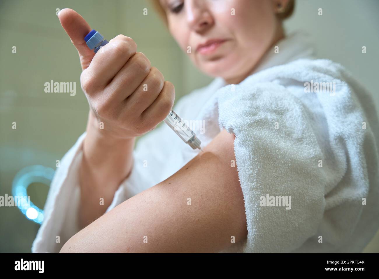Female gives herself an injection in the arm Stock Photo - Alamy