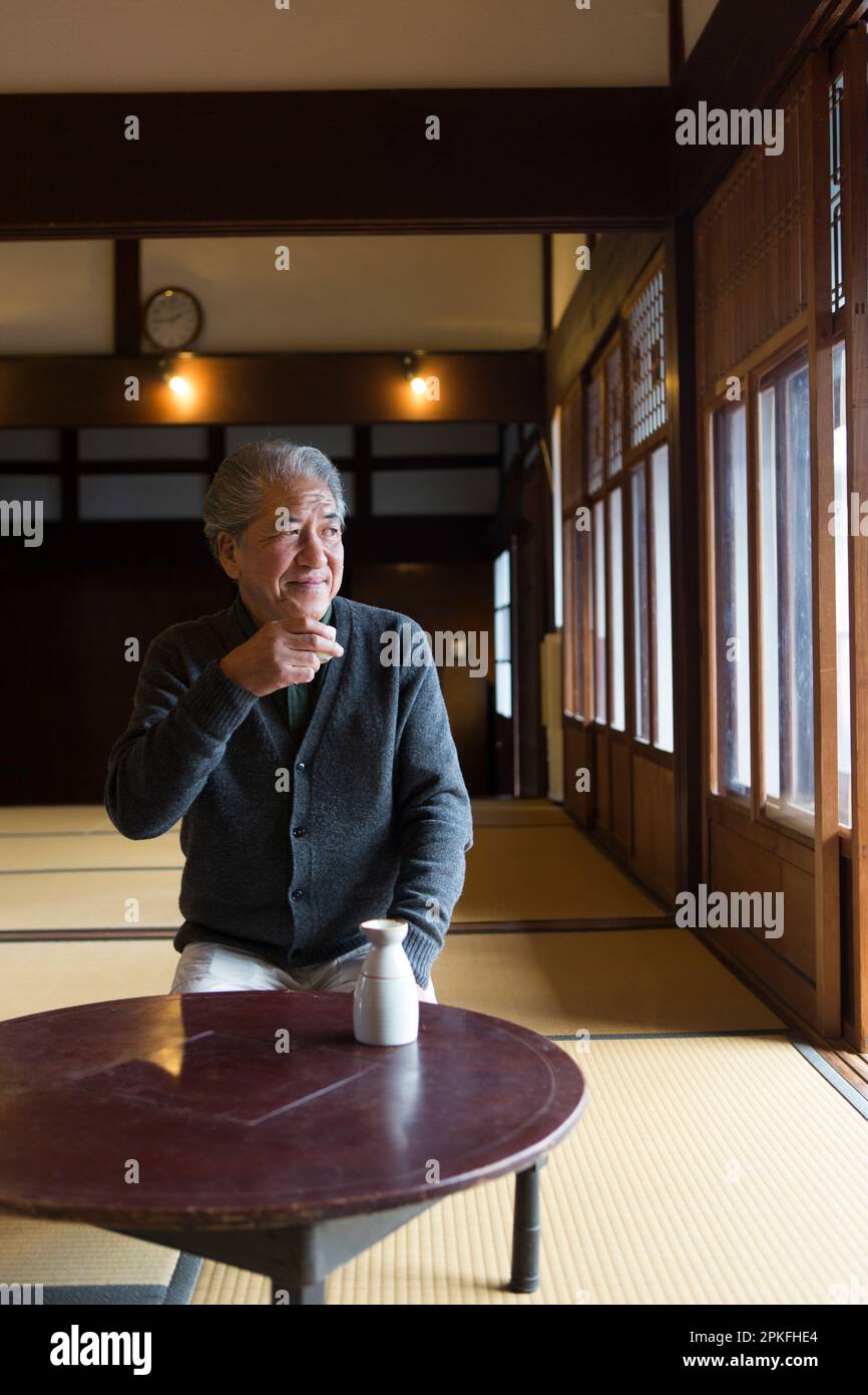 Senior man drinking sake at an old private house Stock Photo - Alamy