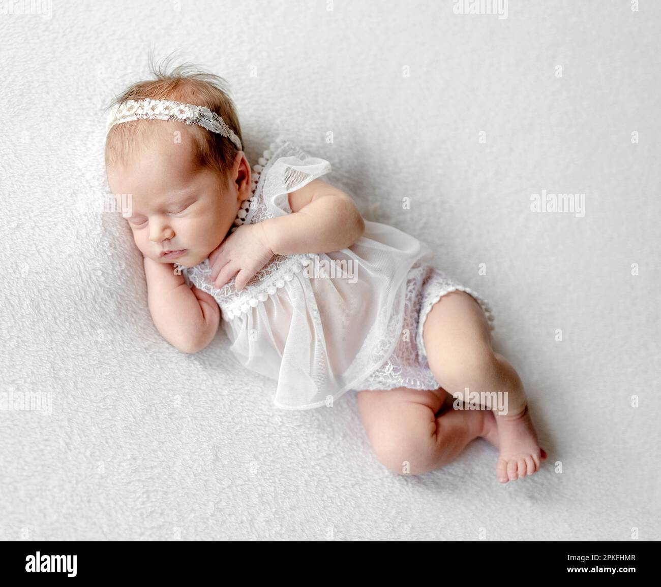 Newborn baby girl wearing wreath and tender dress sleeping holding tiny ...