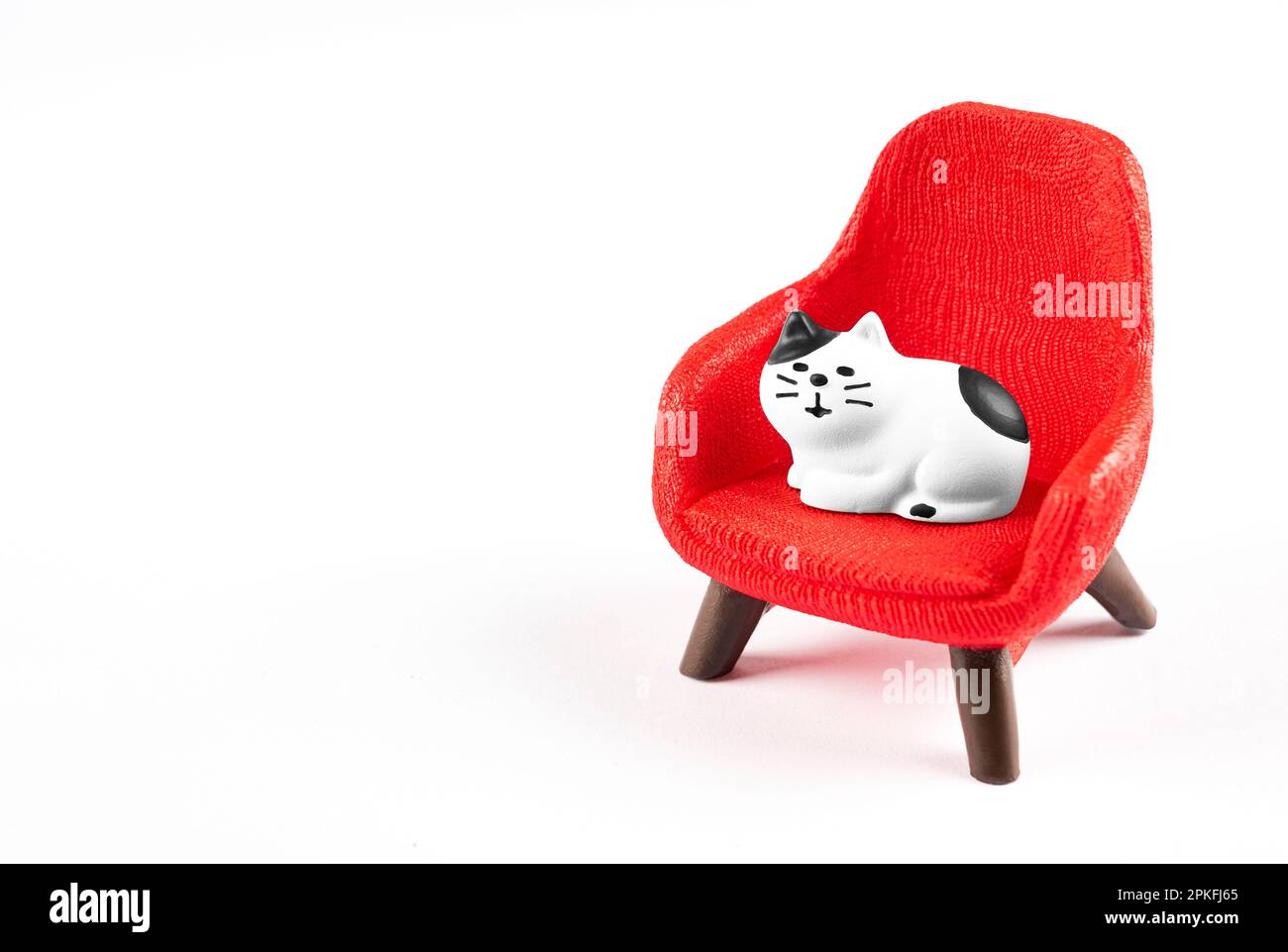 Figure of cute cat in red chair on white background Stock Photo - Alamy