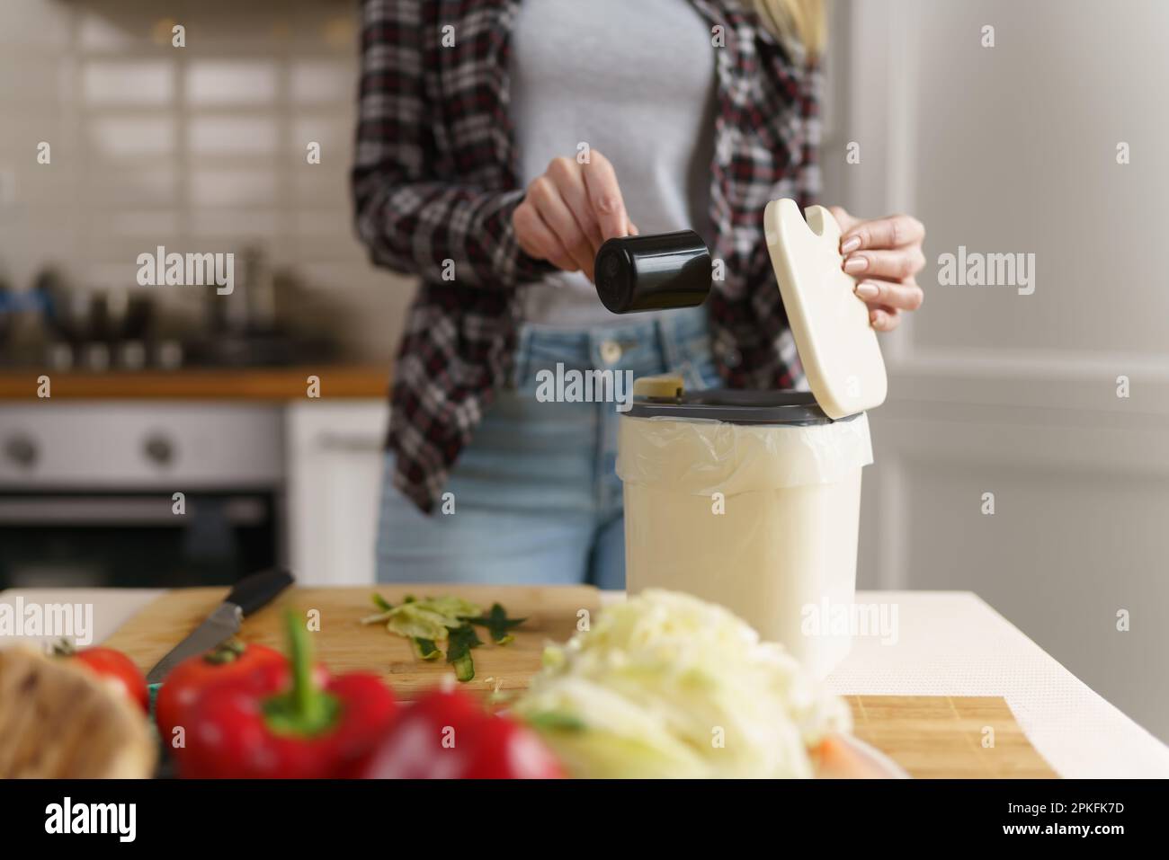 Woman pouring bokashi ferment bran in a compost container for recycling ...