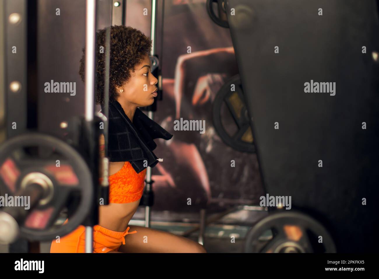 Fitness woman doing the barbell back squat using the power rack in a ...