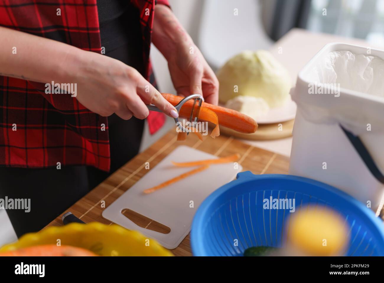 Cook peeling off carrot with a peeler tool. Female person cooking ...