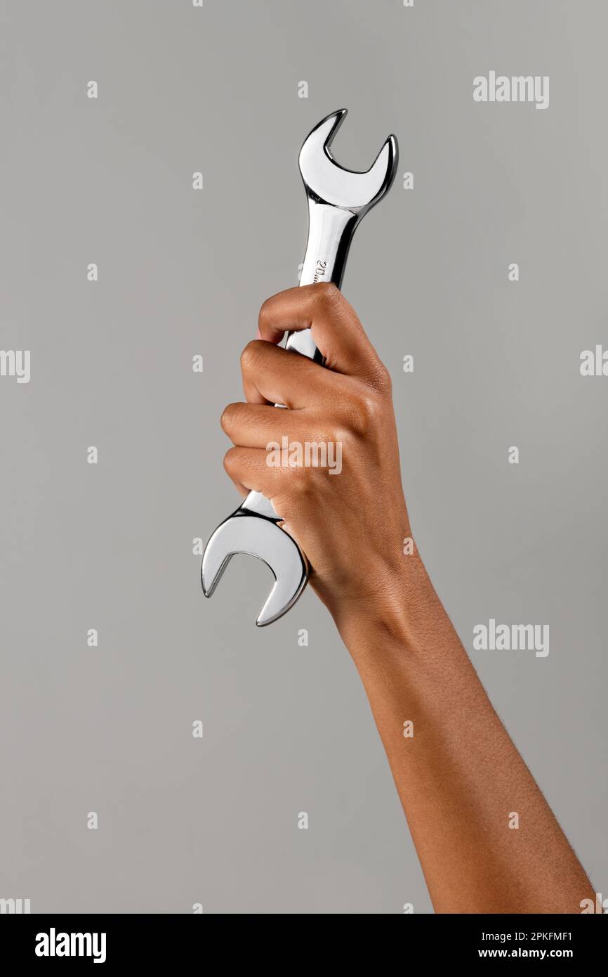 Anonymous African American female demonstrating metal spanner in raised ...