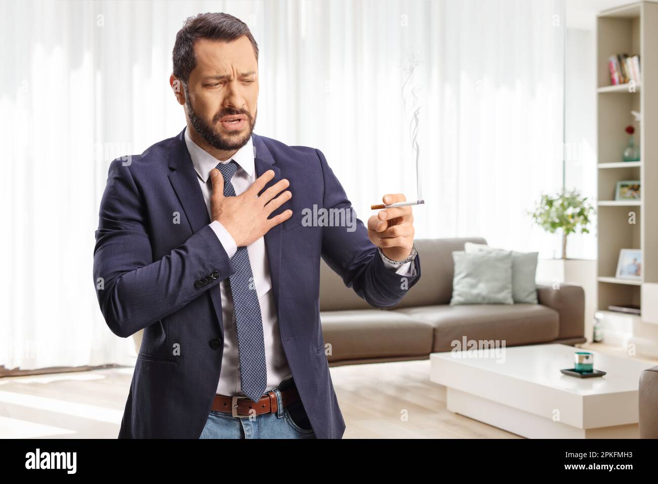 Young man smoking and coughing at home in a living room Stock Photo - Alamy