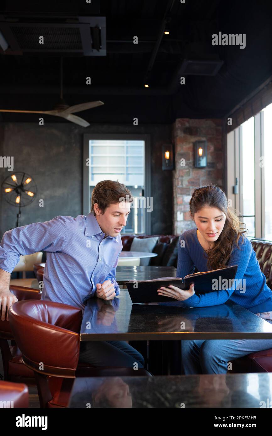 Couple looking at the menu at a café Stock Photo - Alamy