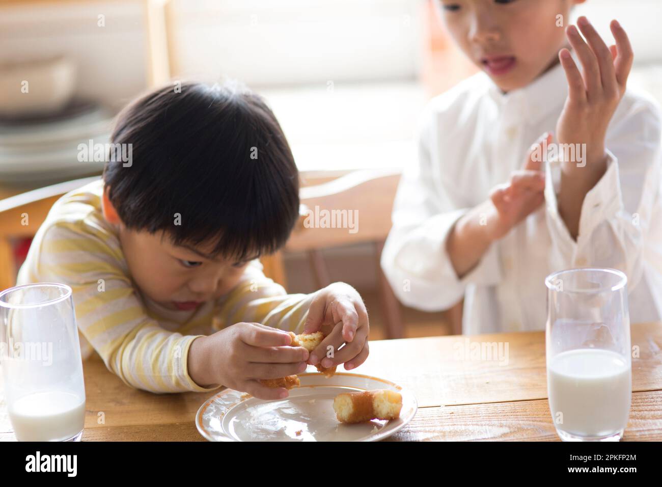 Child eating a donut at the kitchen table Stock Photo - Alamy