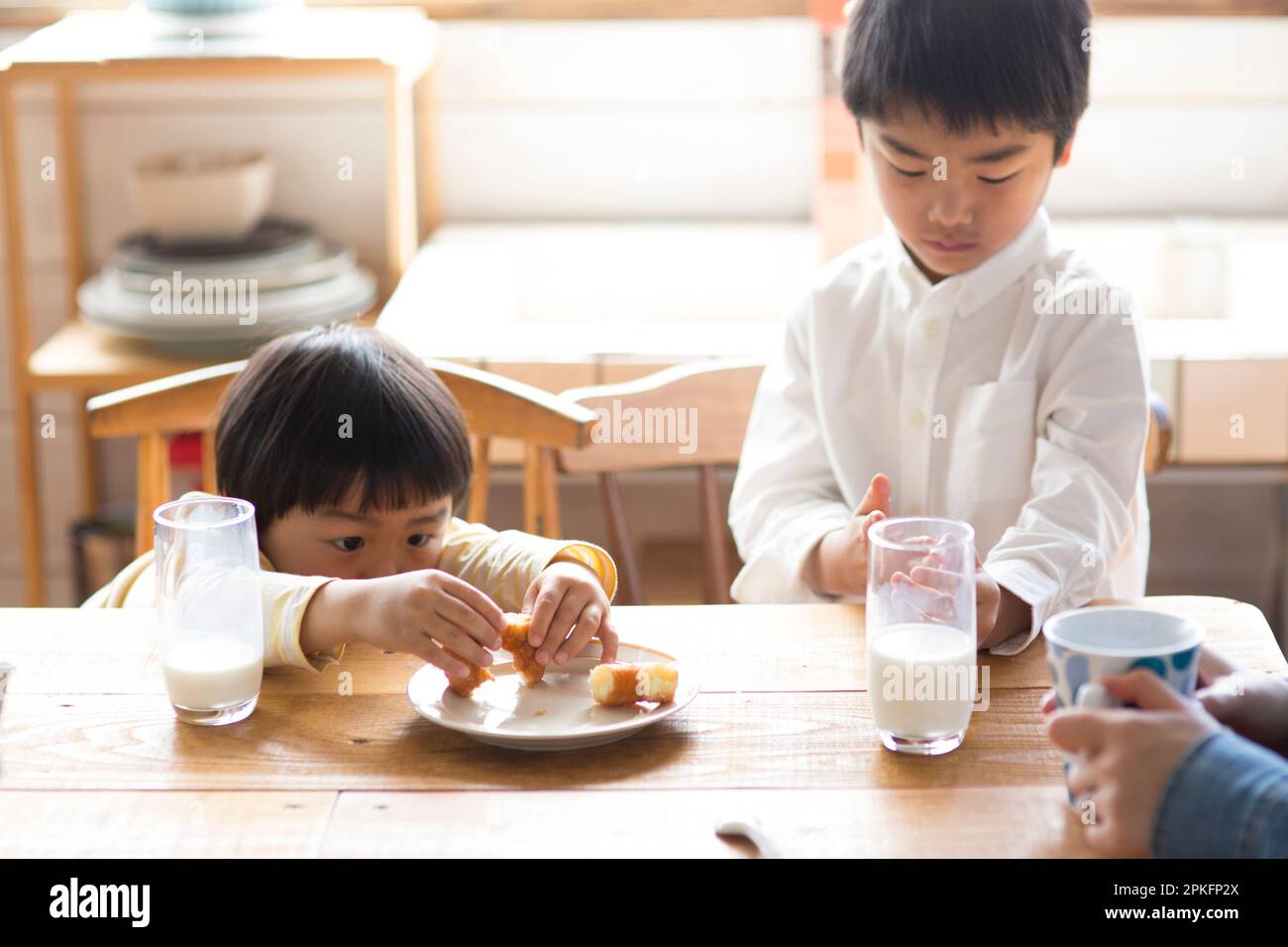 Child eating a donut at the kitchen table Stock Photo - Alamy