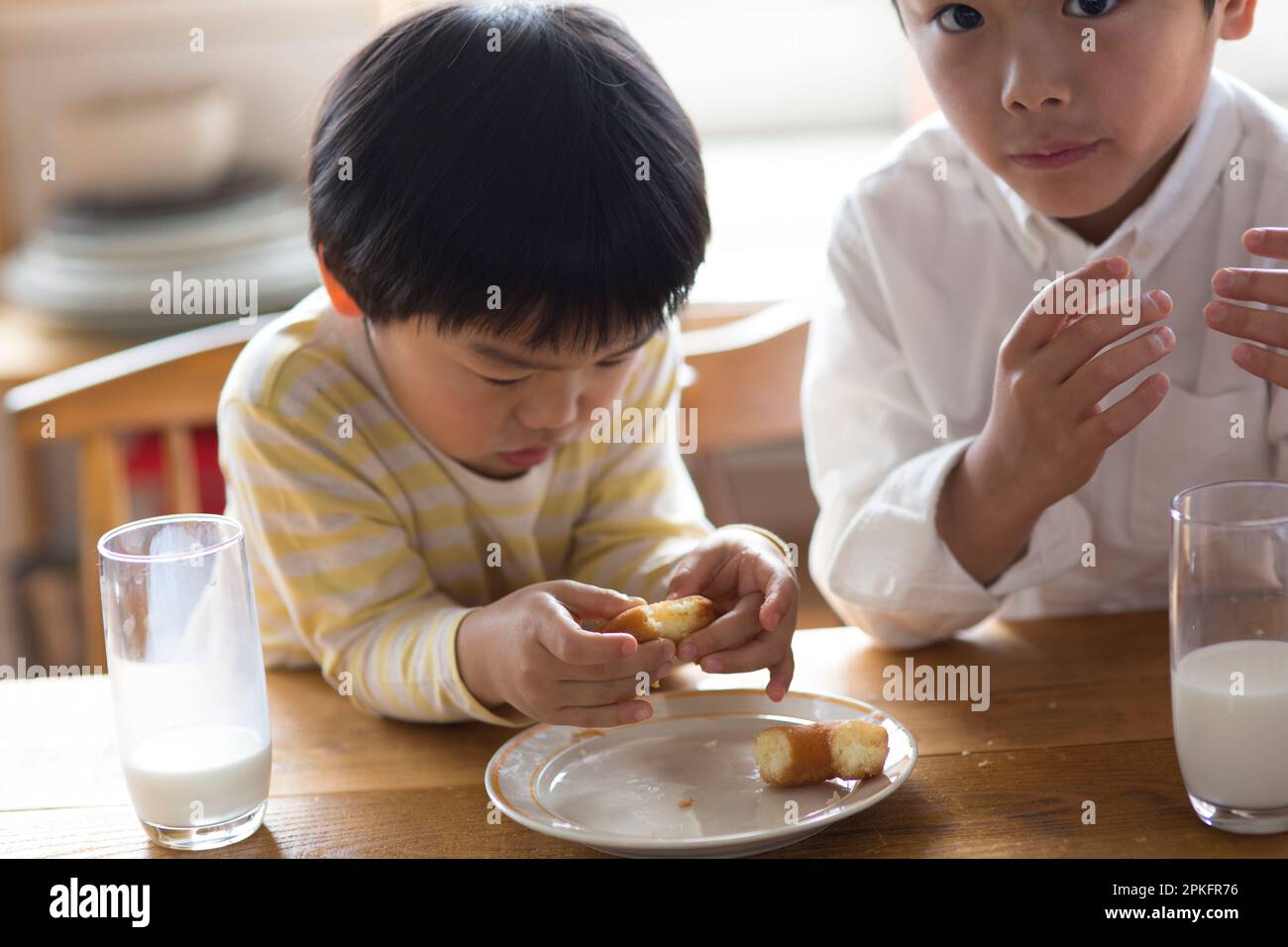 Child eating donut at kitchen table Stock Photo - Alamy