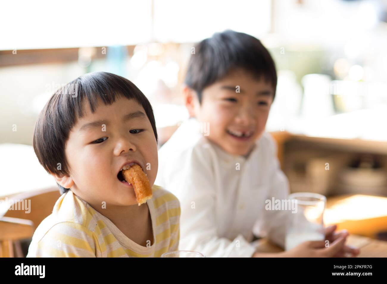 Siblings eating a snack at the kitchen table Stock Photo - Alamy