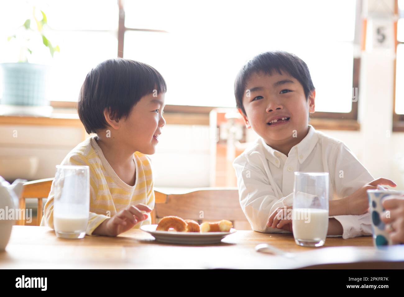Siblings eating snack at kitchen table Stock Photo - Alamy