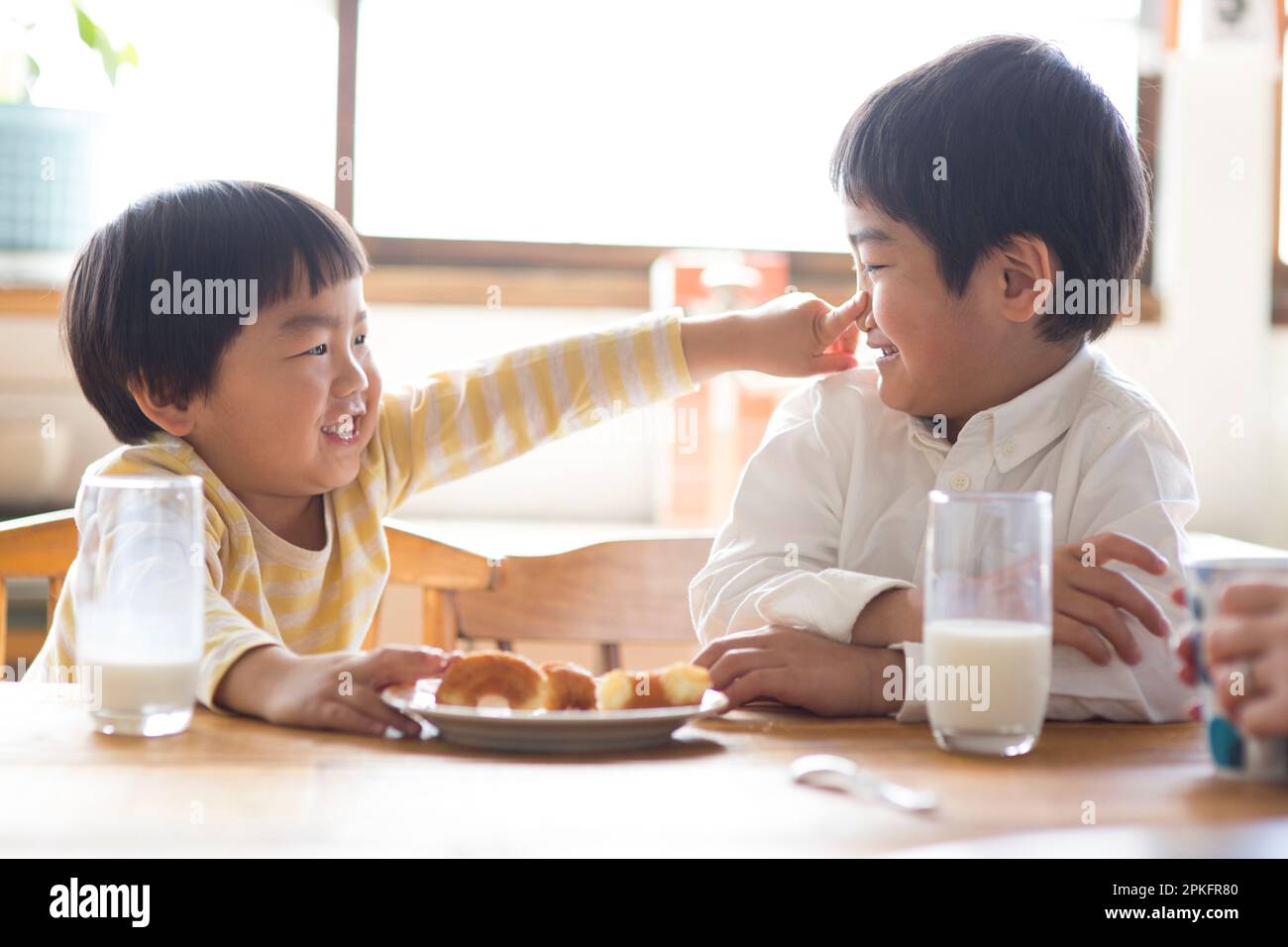 Siblings eating snack at kitchen table Stock Photo - Alamy