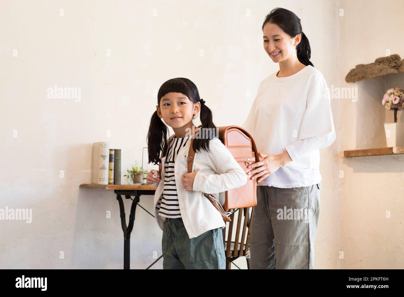 An elementary school girl carrying a school backpack and her mother ...