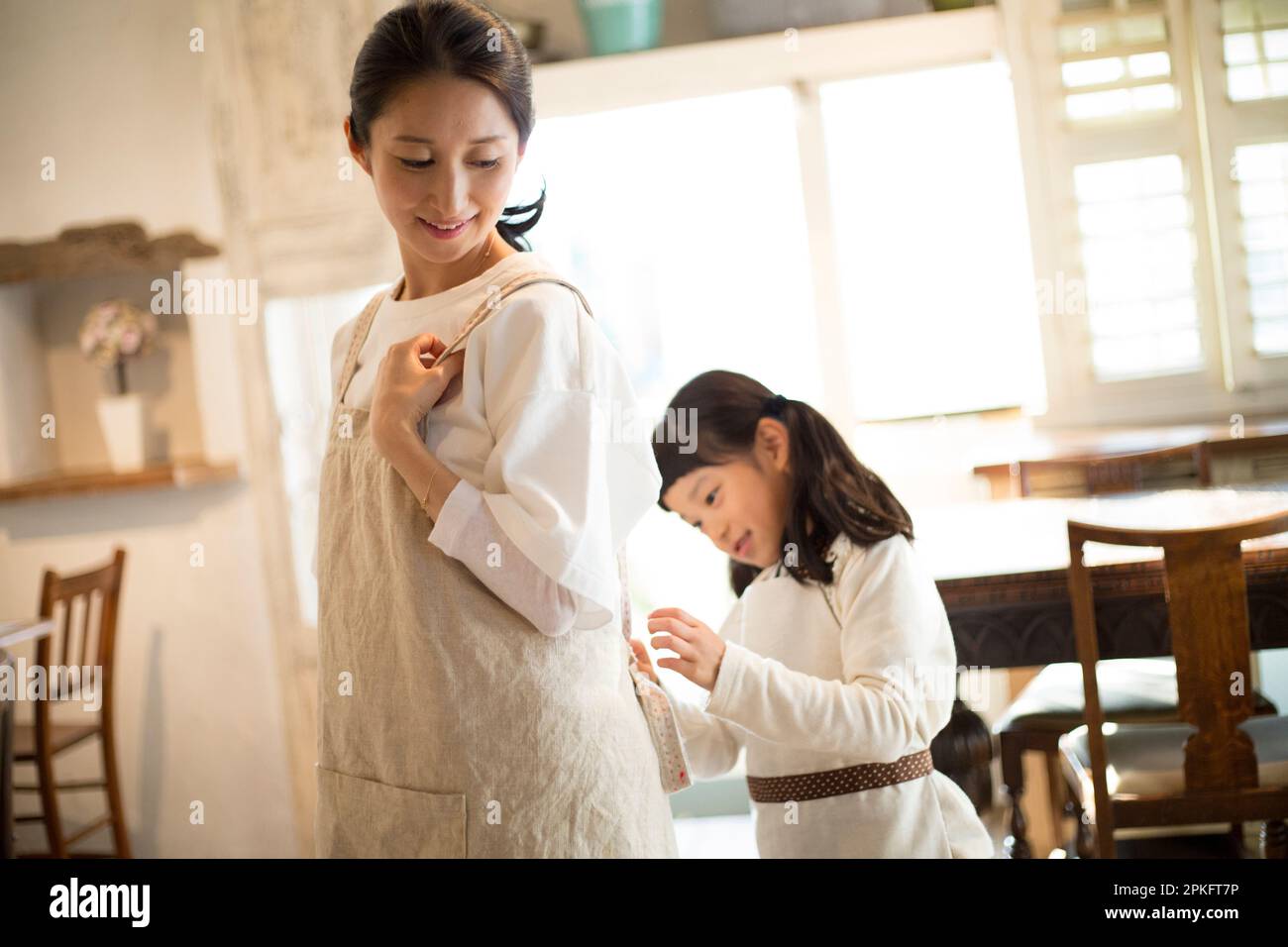Girl tying her mother's apron Stock Photo - Alamy