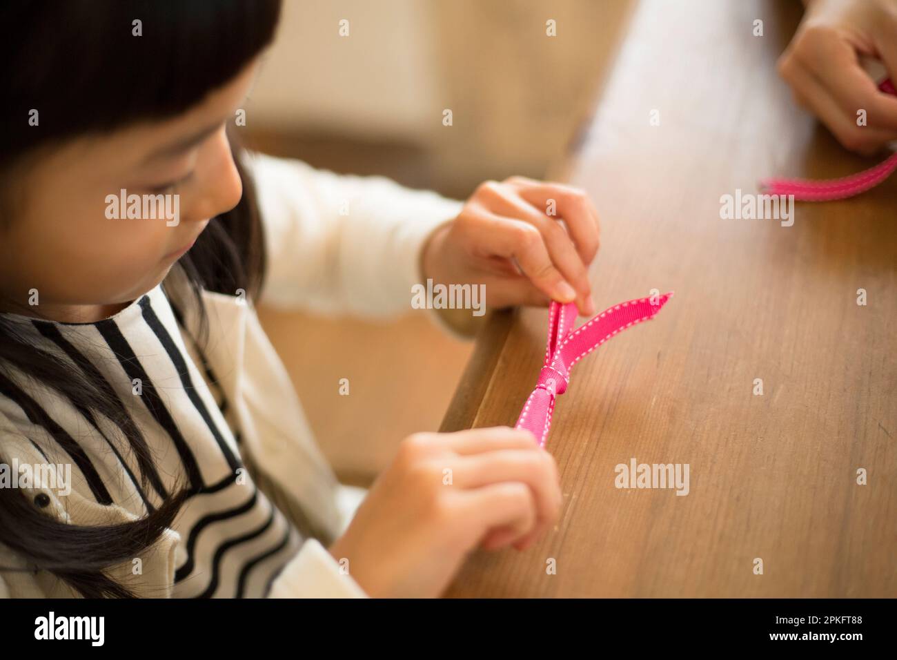 Girl being taught to tie a ribbon by her mother Stock Photo - Alamy