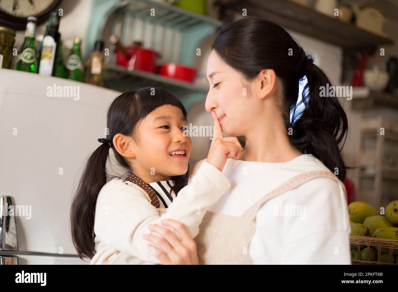 Girl hugging her mother and putting her finger to her mouth Stock Photo ...