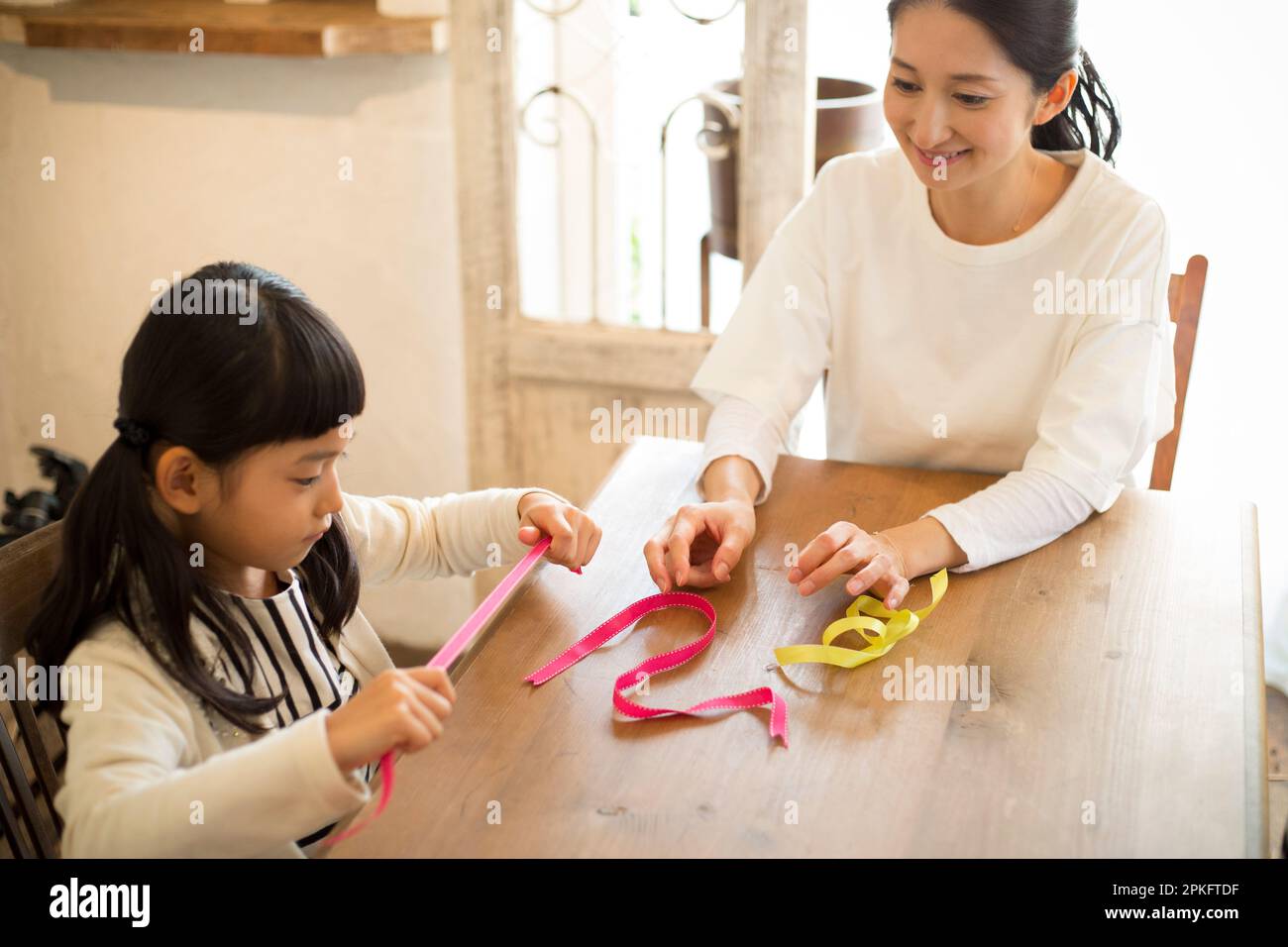 Girl being taught to tie a ribbon by her mother Stock Photo - Alamy