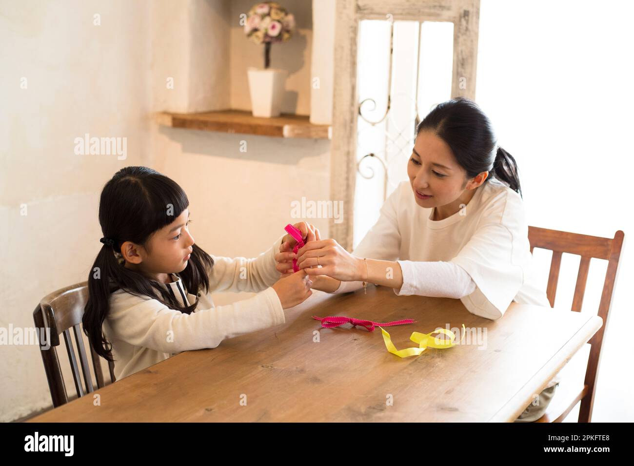 Girl being taught to tie a ribbon by her mother Stock Photo - Alamy
