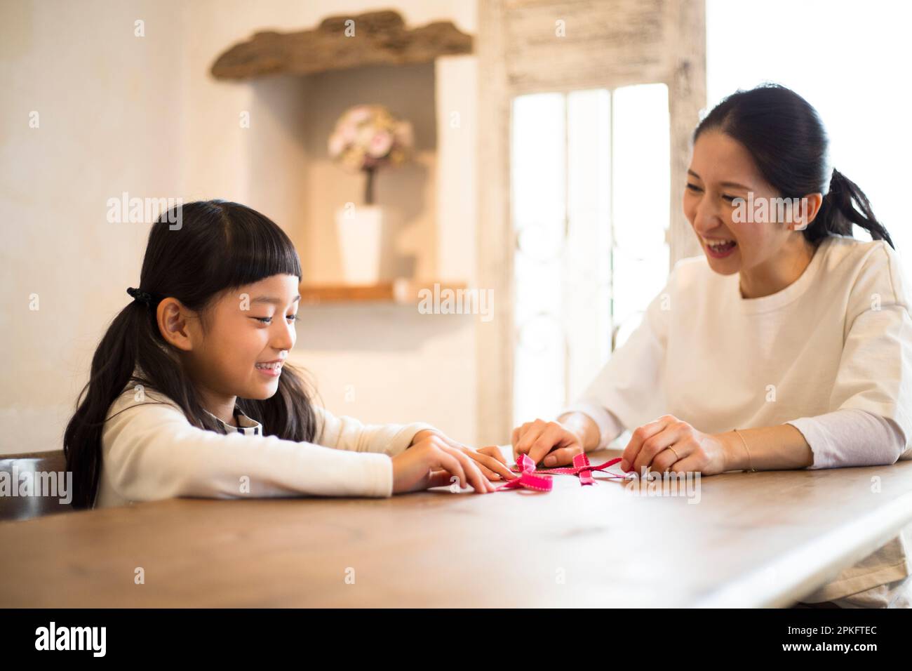 Girl being taught to tie a ribbon by her mother Stock Photo - Alamy