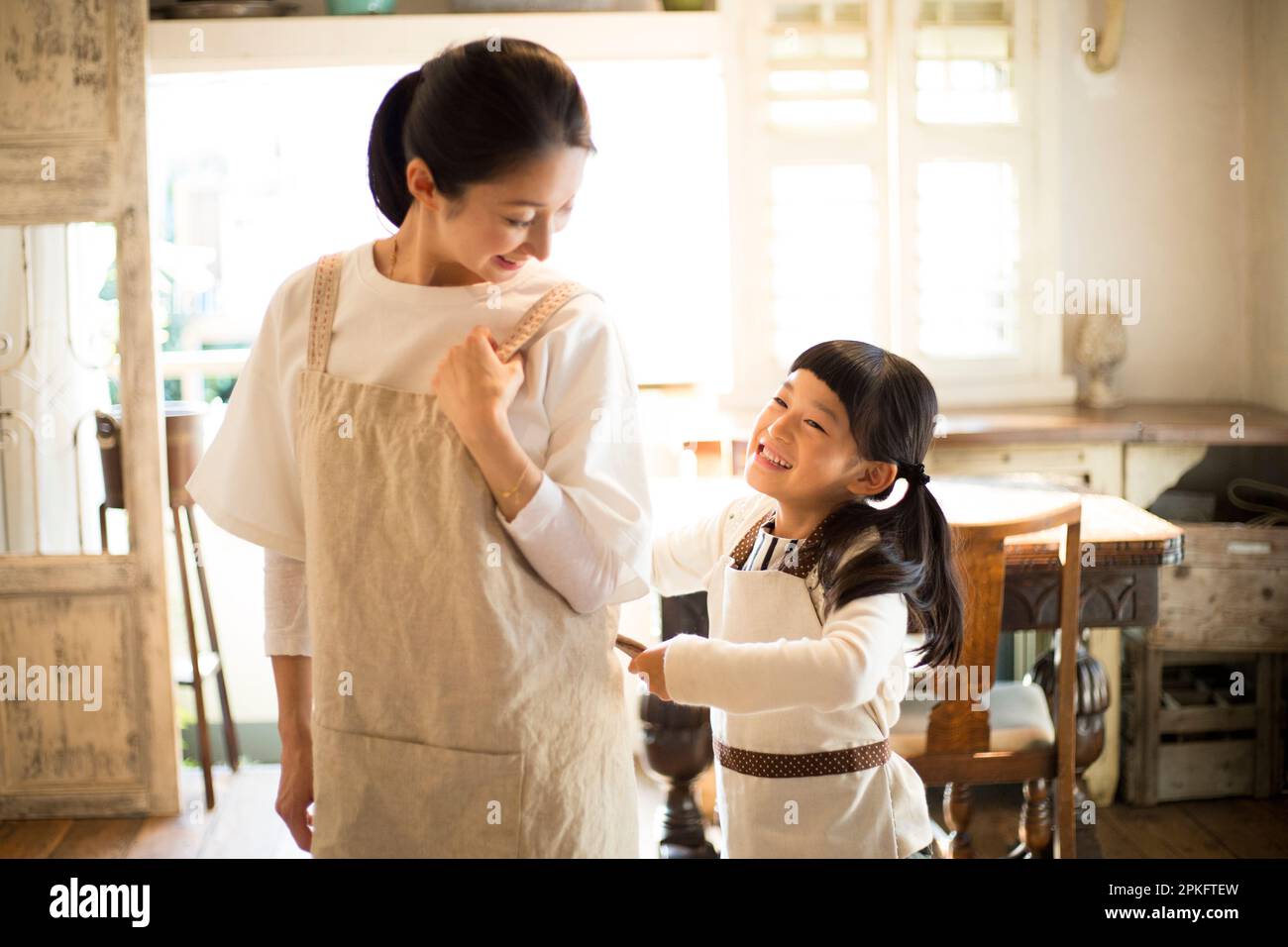 Girl tying her mother's apron Stock Photo - Alamy