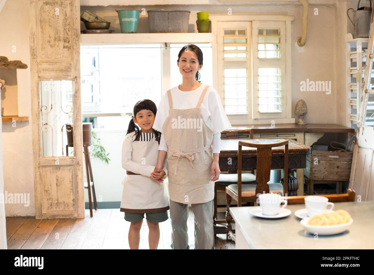 Mother and girl wearing an apron Stock Photo - Alamy