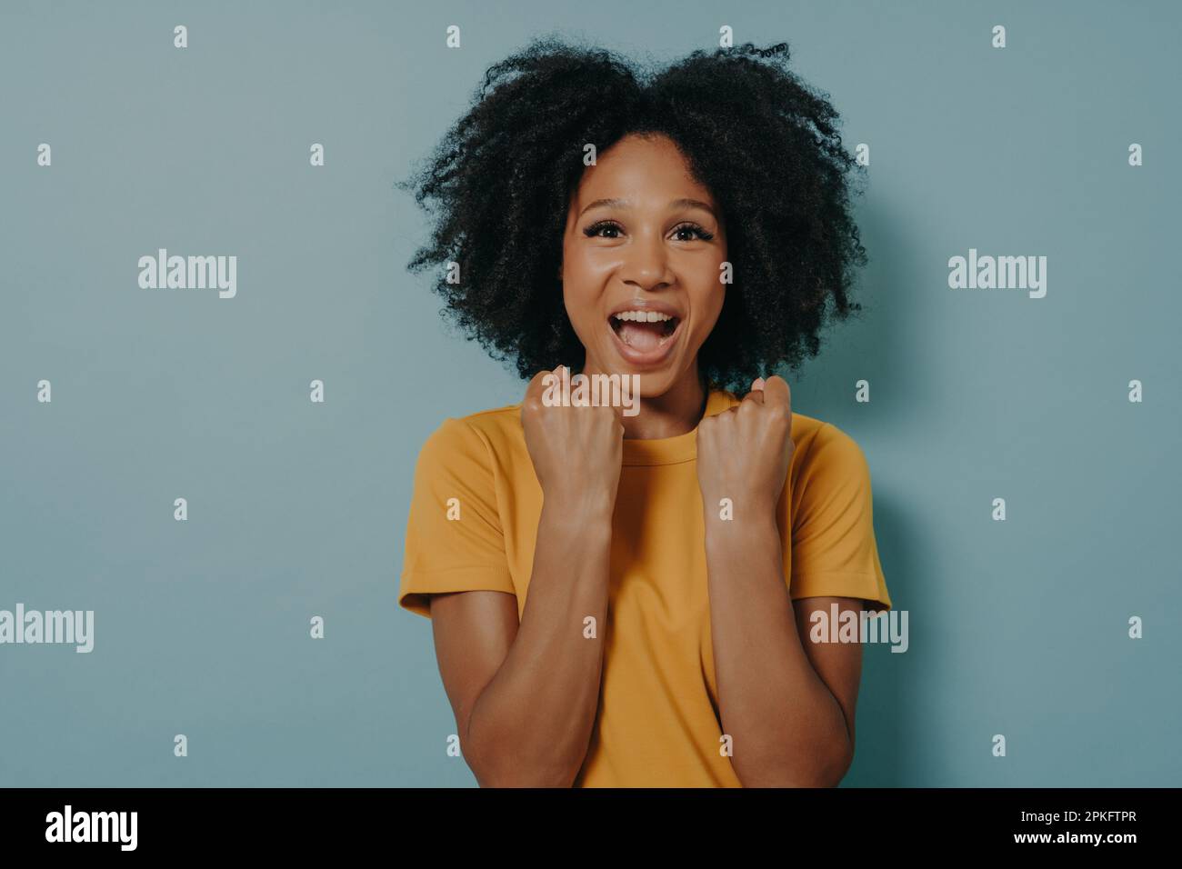 Happy dark skinned woman enjoys wonderful life, clenches fists with joy ...