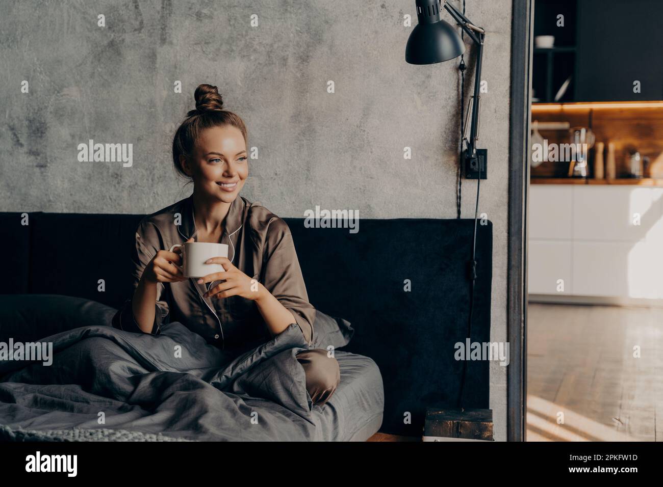 Happy smiling caucasian female in pajama enjoying morning cup of coffee ...