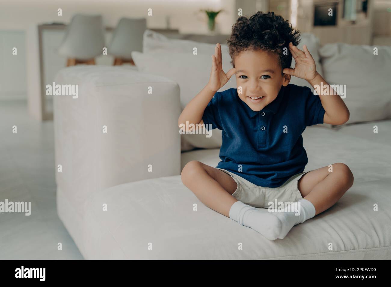 Full length shot of happy playful curly mulatto child holding his hands ...
