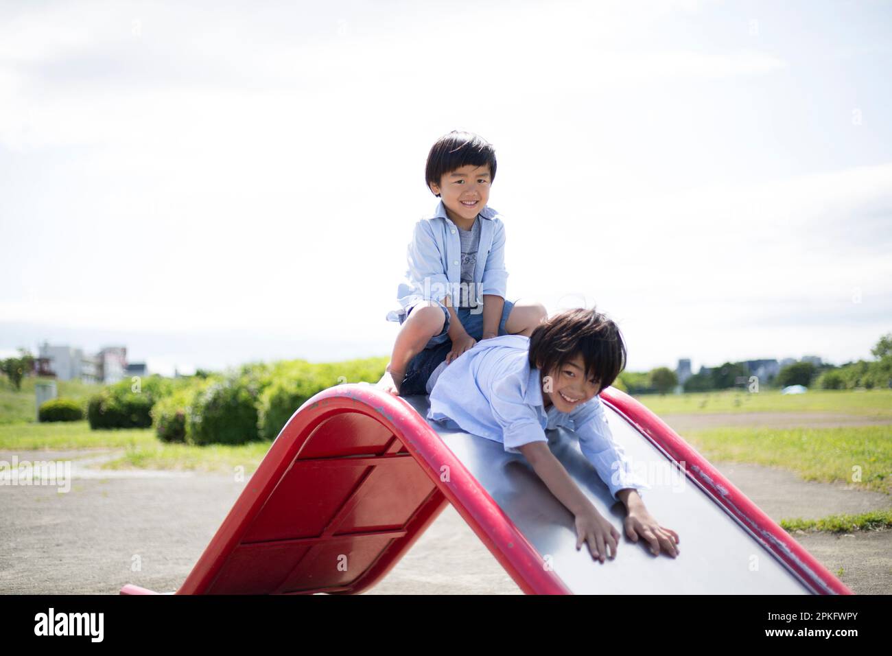 Boys playing on the slide at the park Stock Photo - Alamy