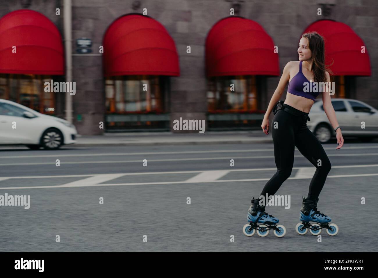 Full length shot of slim active young woman rides rollerblades for ...