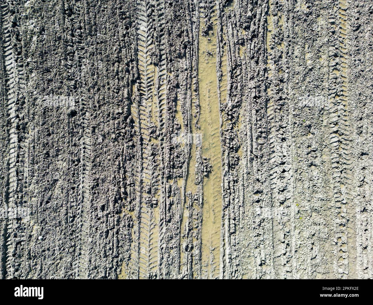 Top down drone view of a muddy farm field showing tyre tracks from a ...