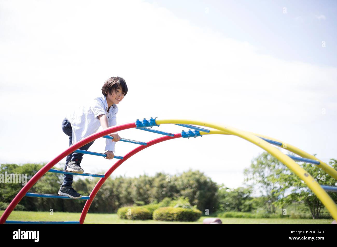 Elementary school boy playing on the playground equipment at the park ...