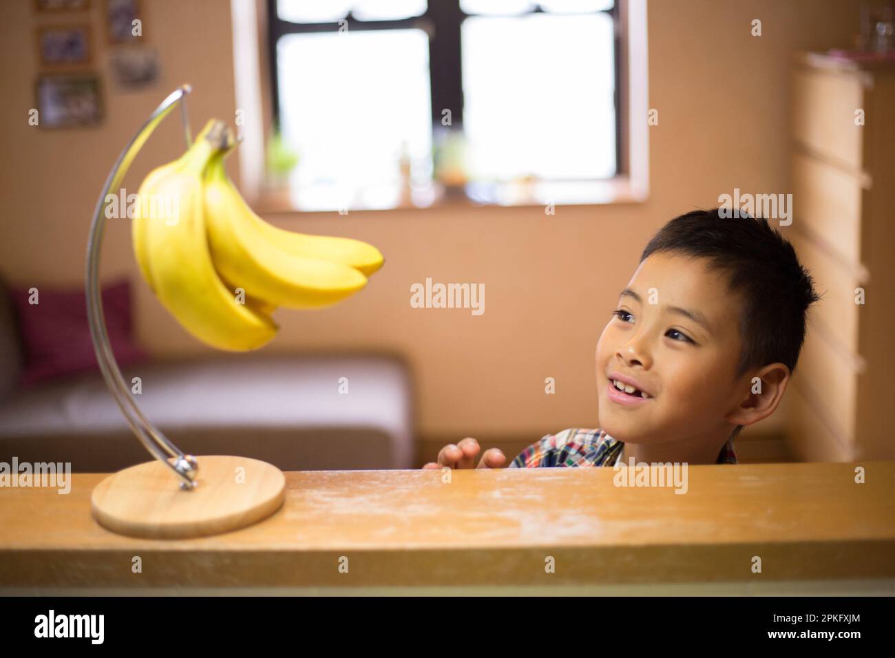 Elementary school boy looking at bananas in the living room Stock Photo ...