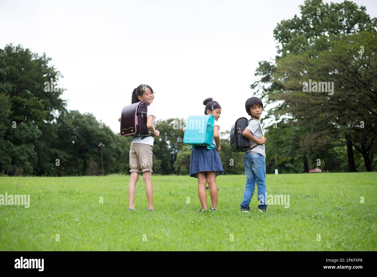 Elementary school children looking back at a meadow in a park with ...
