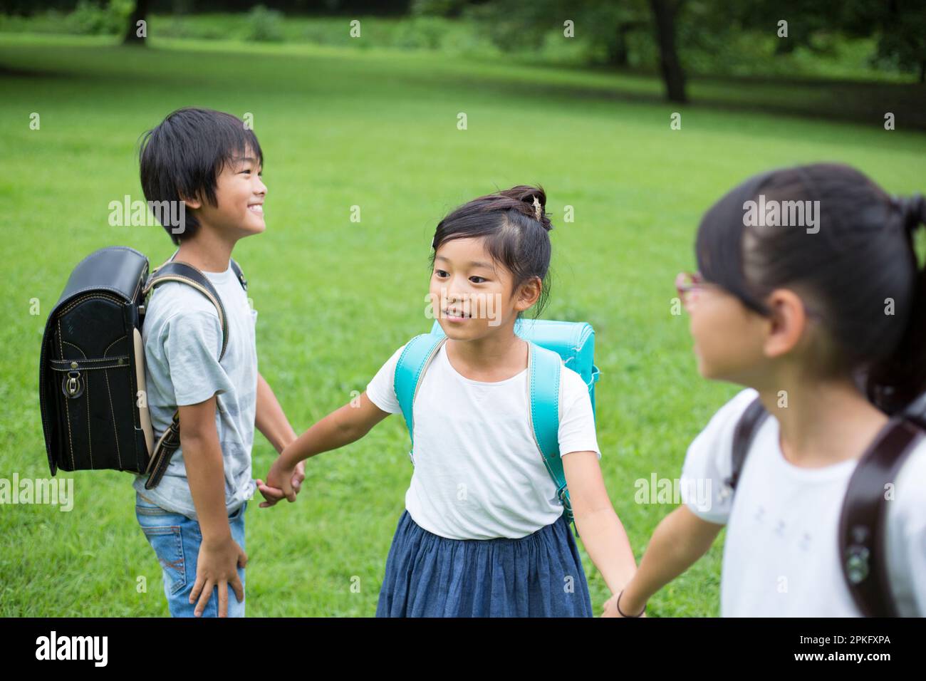 Elementary school students with school backpacks on their backs holding ...