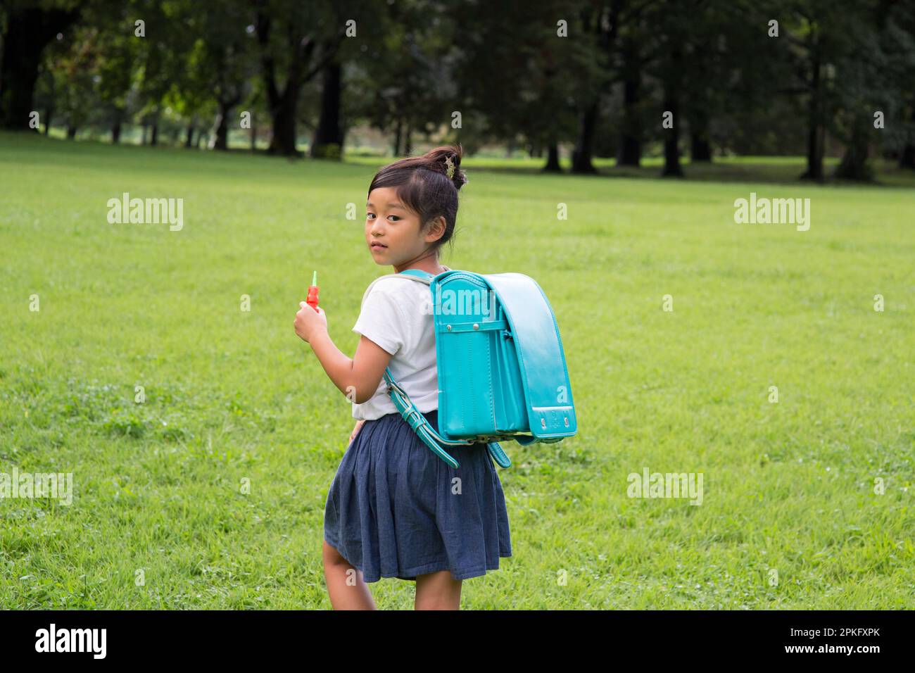 Elementary school girl with school backpack playing with soap bubbles ...