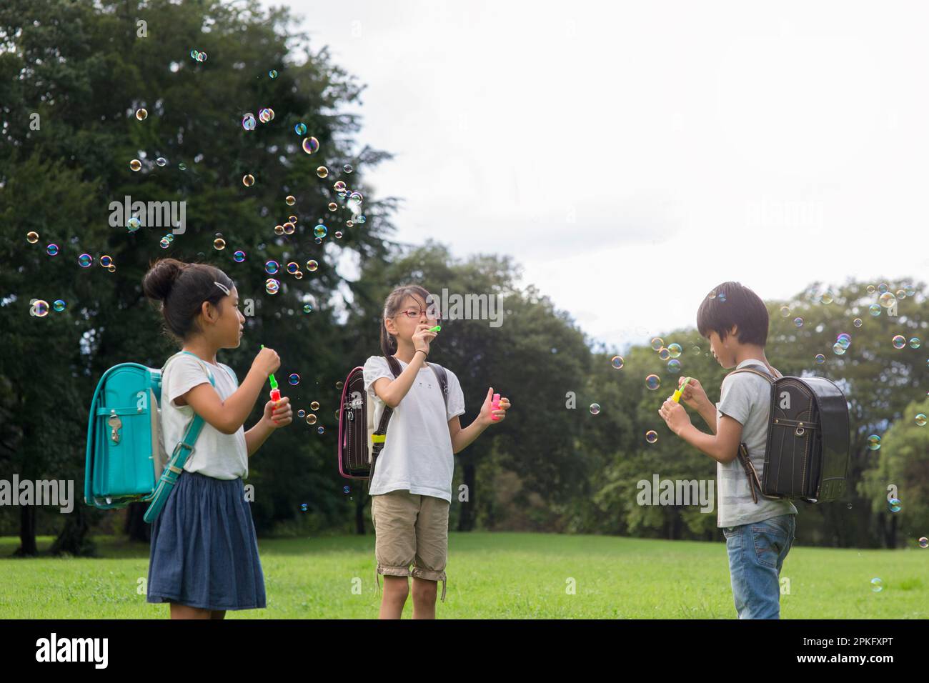 Elementary school students with school backpacks playing with soap ...