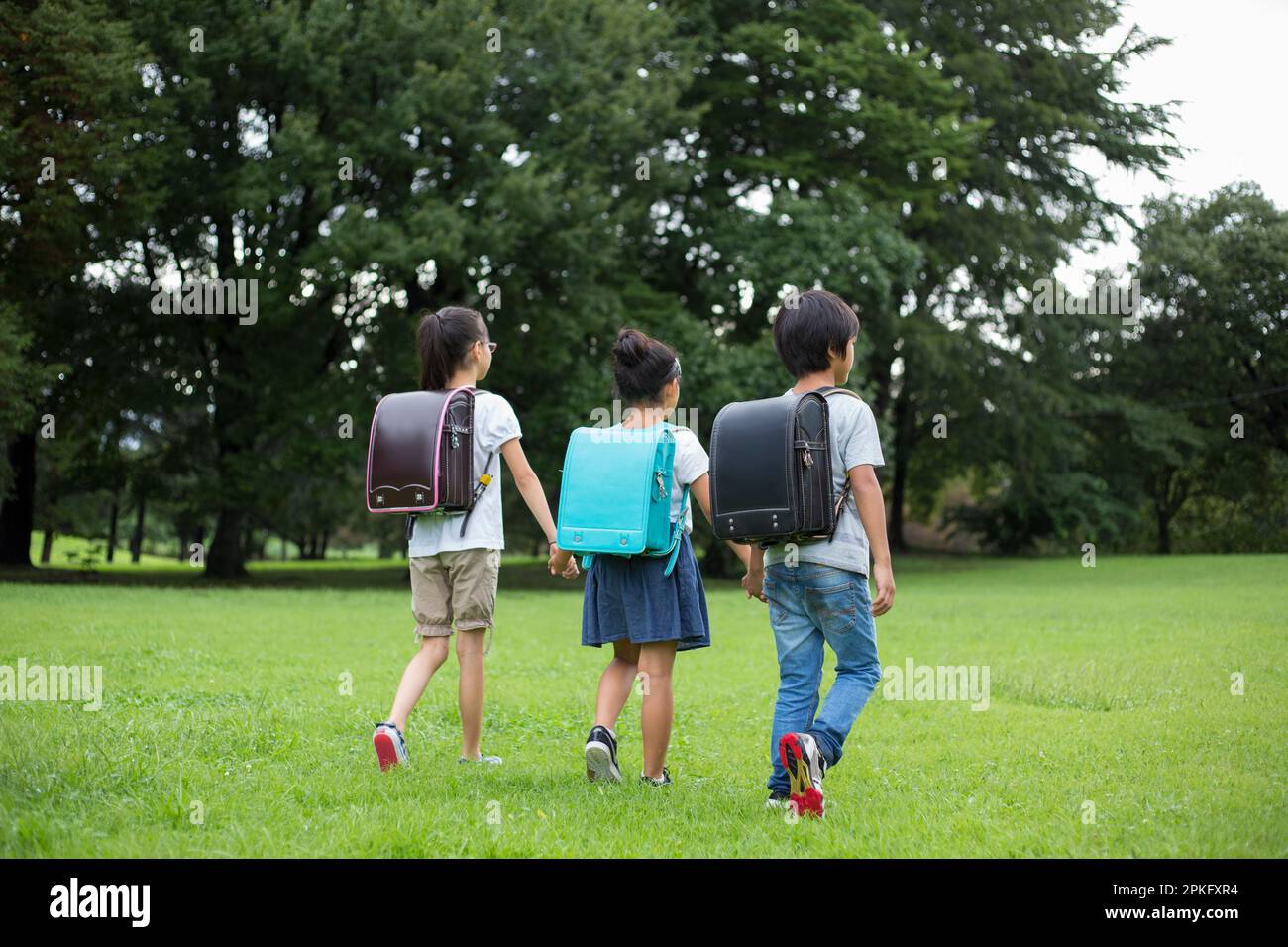 Elementary school students with school backpacks walking hand in hand ...