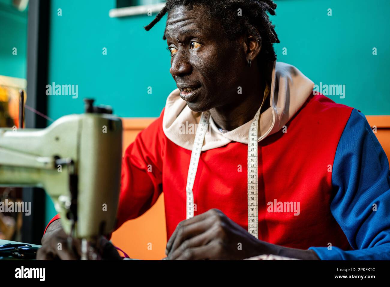 African adult tailor at work, artisan clothing manufacturer sewing with ...