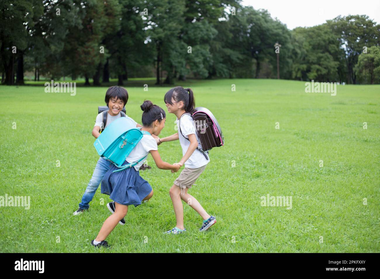 Elementary school students with school bags on their backs holding ...